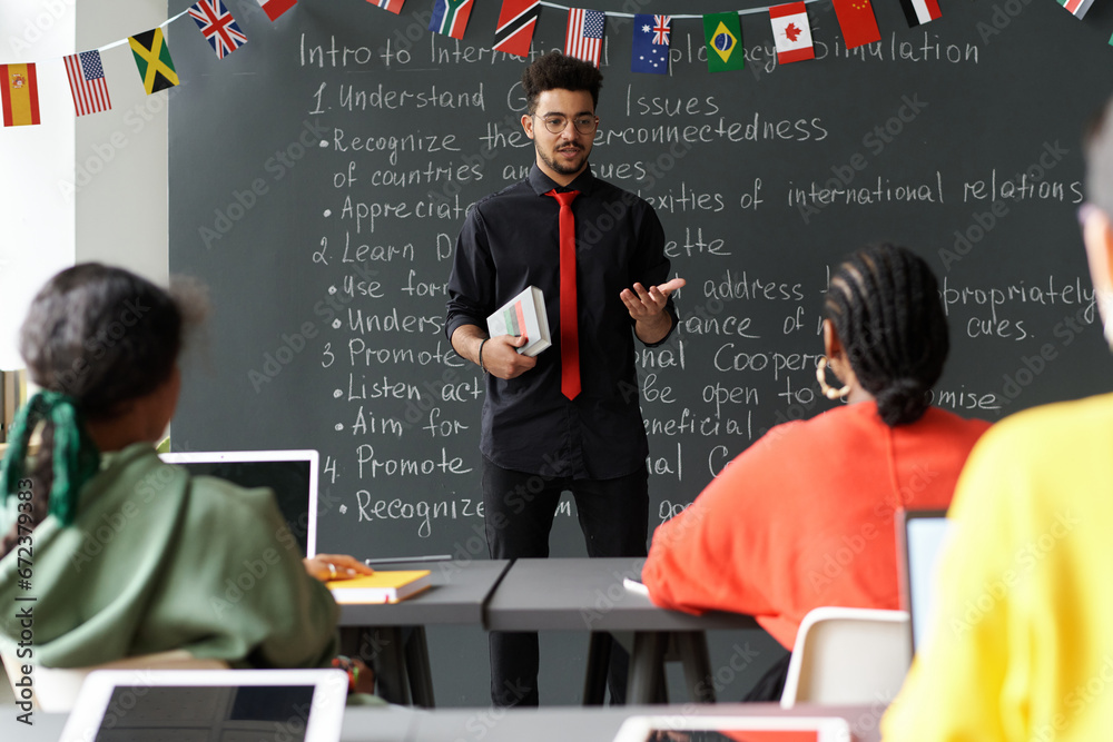 Young teacher standing near the blackboard and having lesson with ...