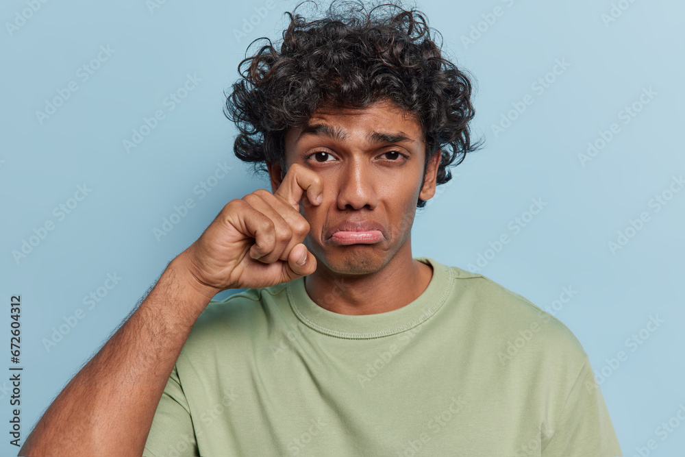 Upset crying young Hindu man wipes tears has doleful expression cries ...