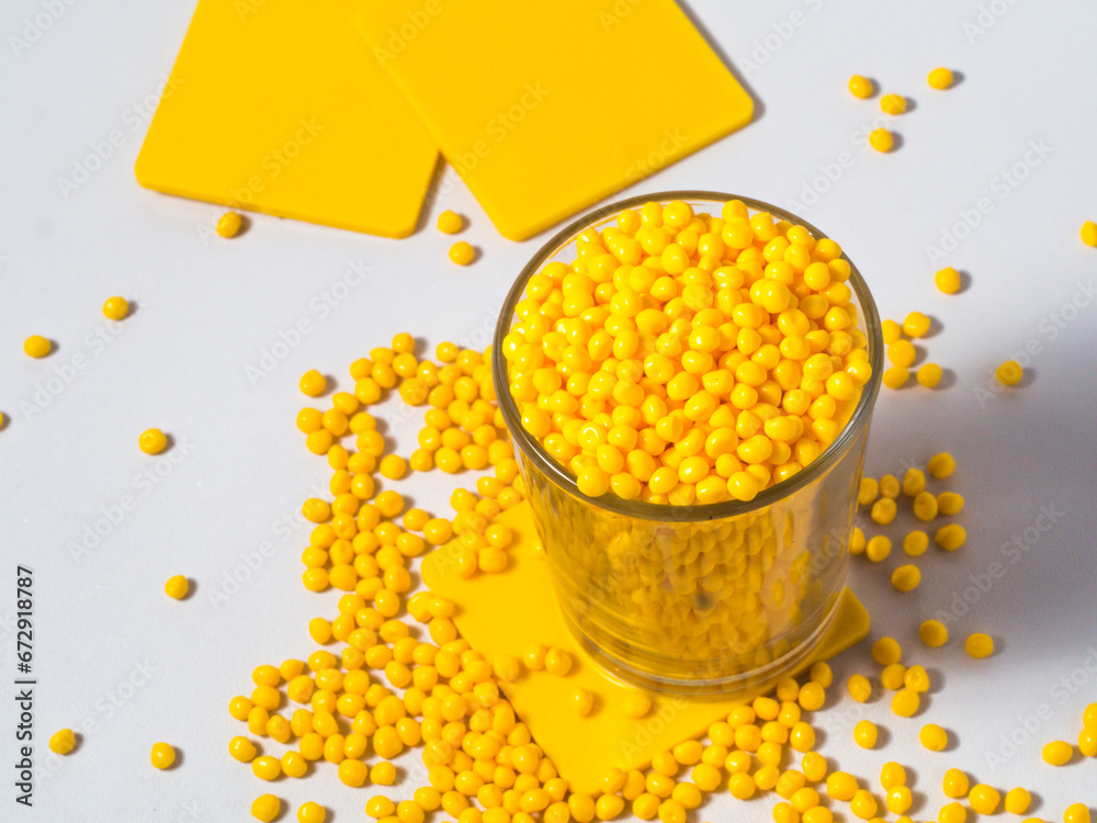 Yellow masterbatch granules in a glass cup isolated on a white ...