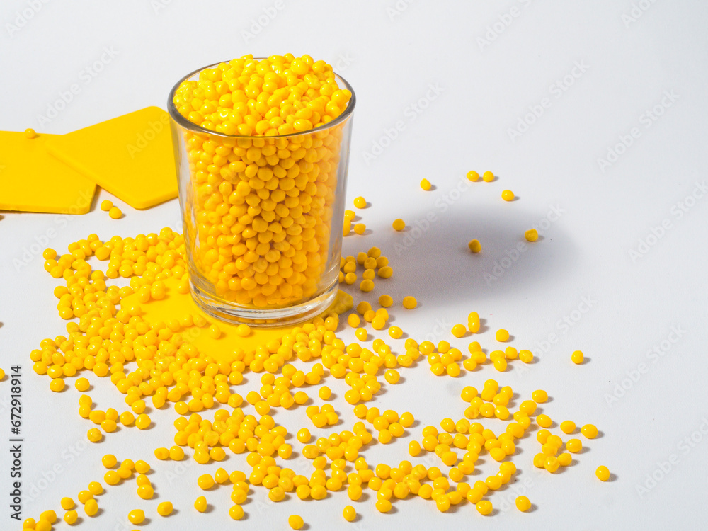 Yellow masterbatch granules in a glass cup isolated on a white ...