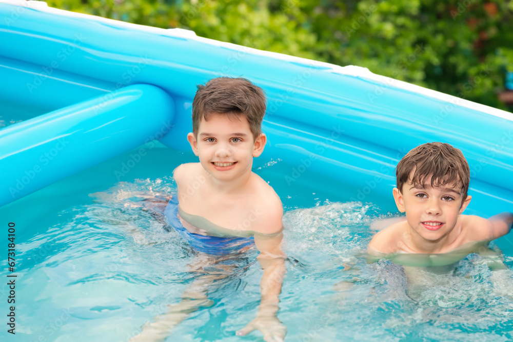 boys swim in the pool. little boys in nature swim in a large pool, two ...