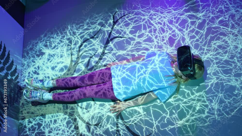 Child girl with virtual reality glasses laying on the VR room floor ...