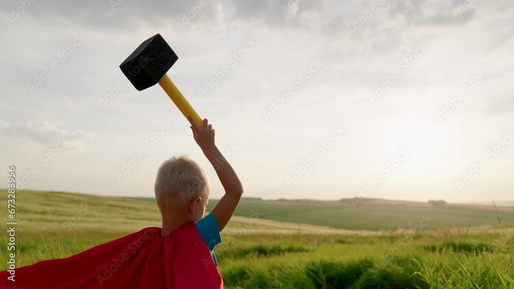 Child plays superhero from comic book, child holds hammer in his hand ...