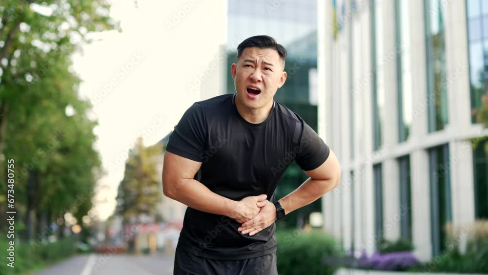 Asian sports man experiences a sharp pain in his right side during a ...