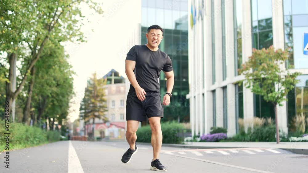 Asian runner athlete with muscle pain in city street. Man massaging ...