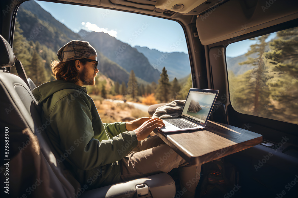 Young man working on computer in camper van. Road trip, motor home ...