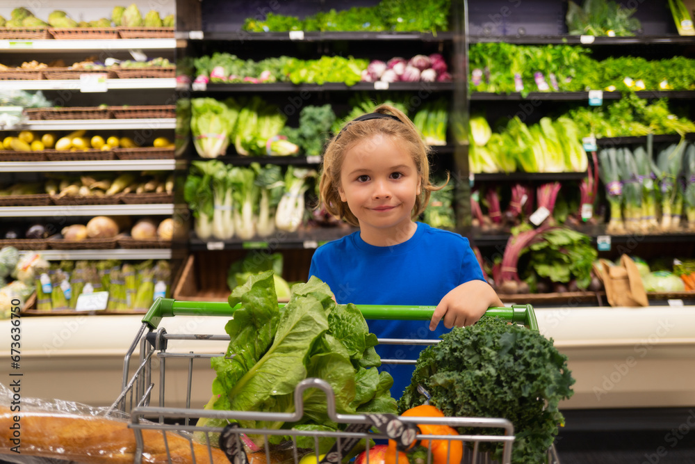 Kid with shopping cart and vegetables at grocery store. Shopping with ...
