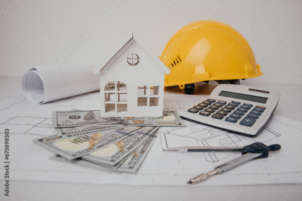 Construction drawings with helmet, calculator and model of house, cost ...