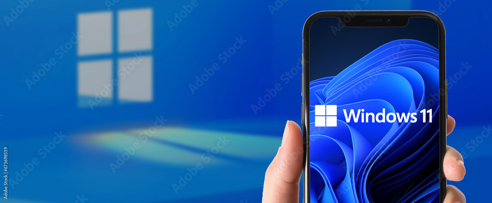 Hands of unrecognizable man holding smartphone with Windows 11 logo on ...