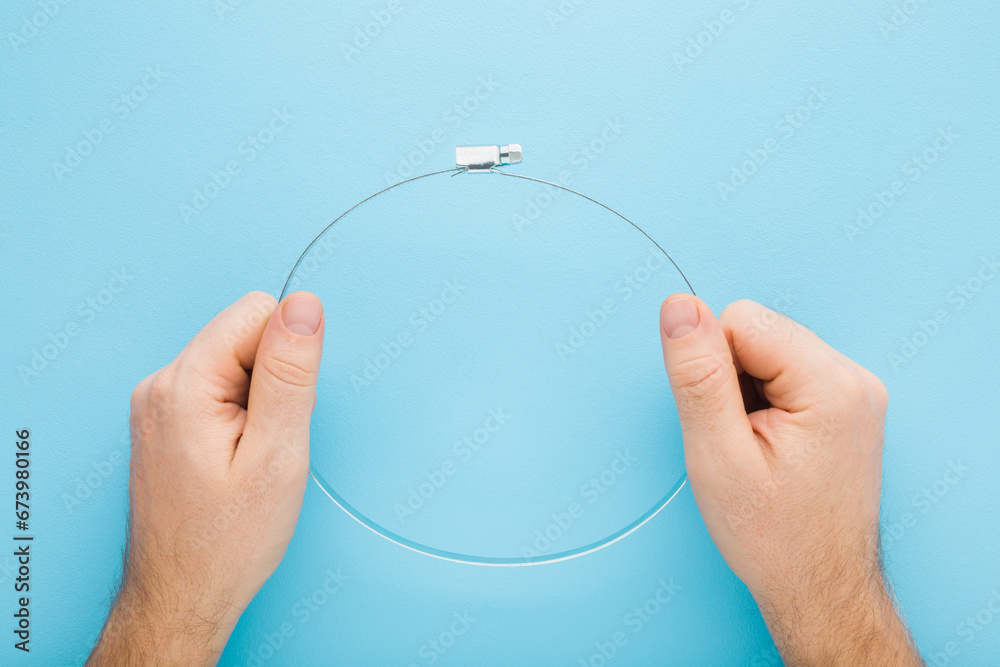 Young adult man hands holding and showing new metal hose clamp on light ...