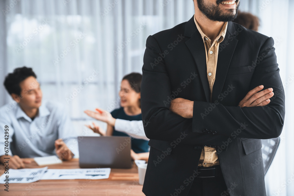 Businessman poses confidently with diverse coworkers in busy meeting ...