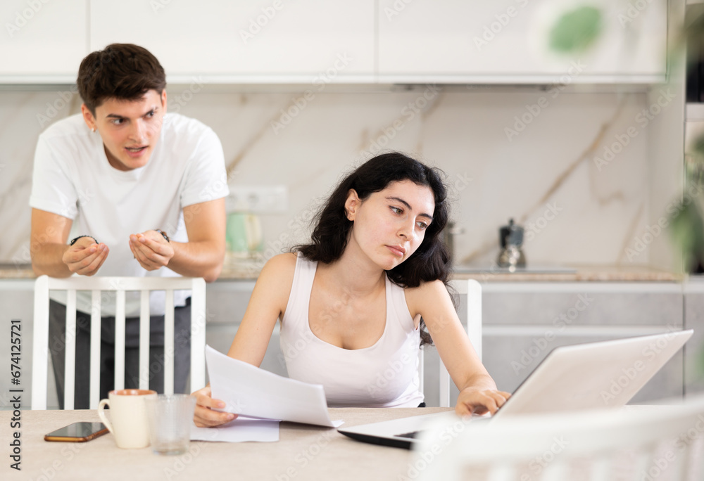 Sad and tired freelancer wife works at home on laptop and listens to ...