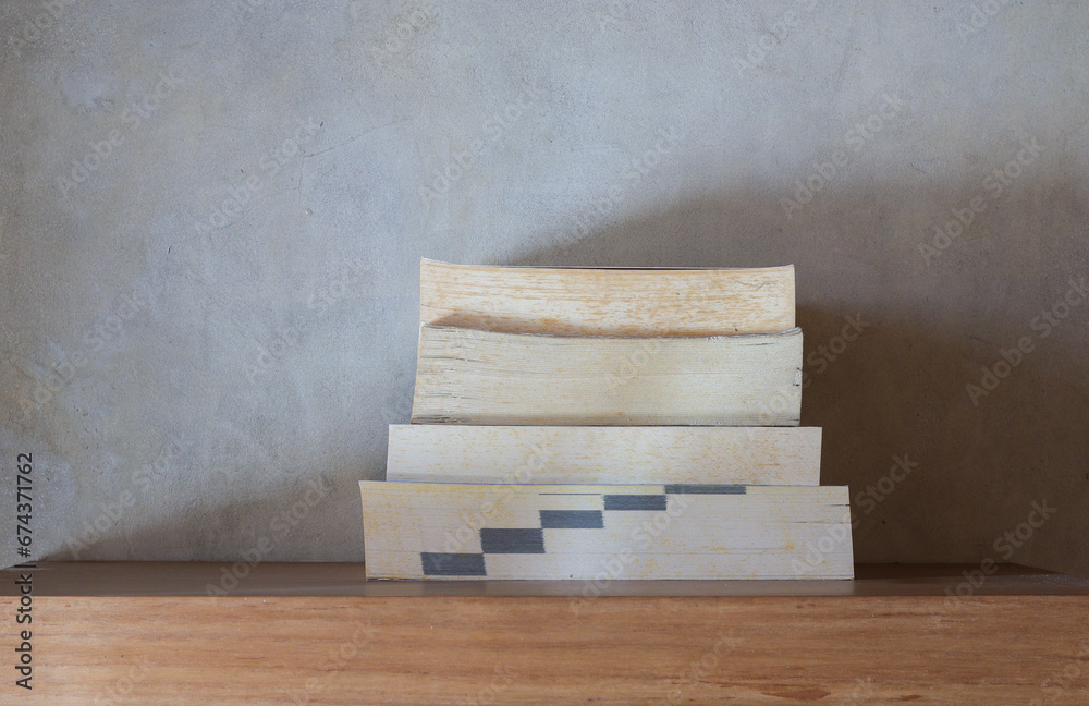 Stack of yellowish and vintage books on floating wooden bookshelf ...