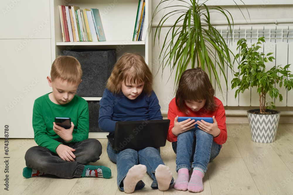 Children sit on the floor and use electronics to learn, play and ...