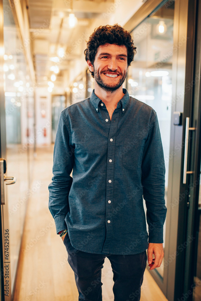 Content successful young man in casual outfit standing in hallway of ...