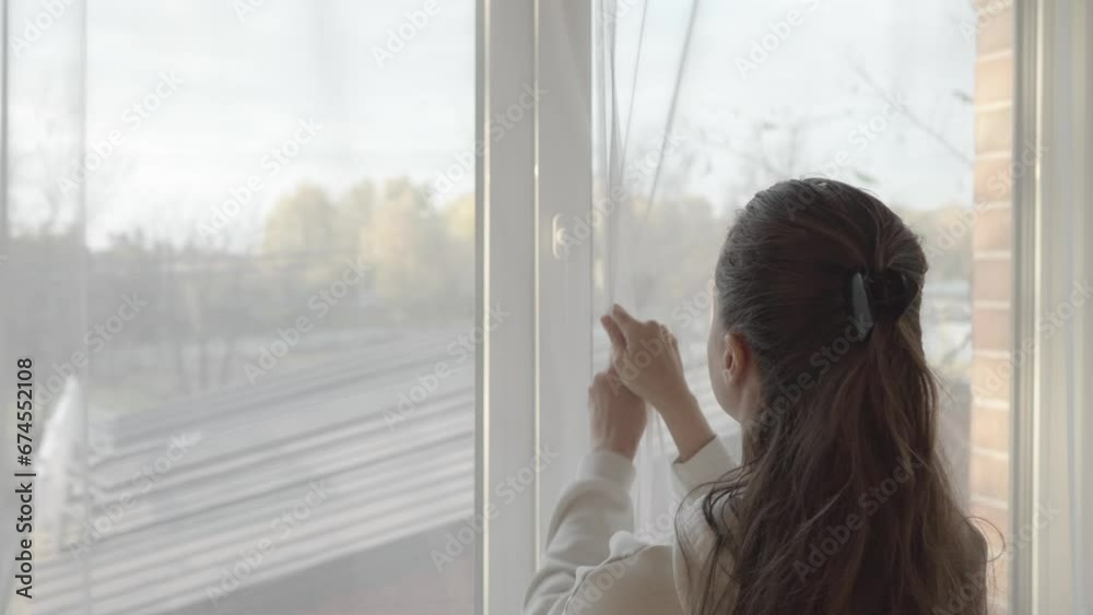 The woman tightly closes the slightly ajar window, turns the handle on ...
