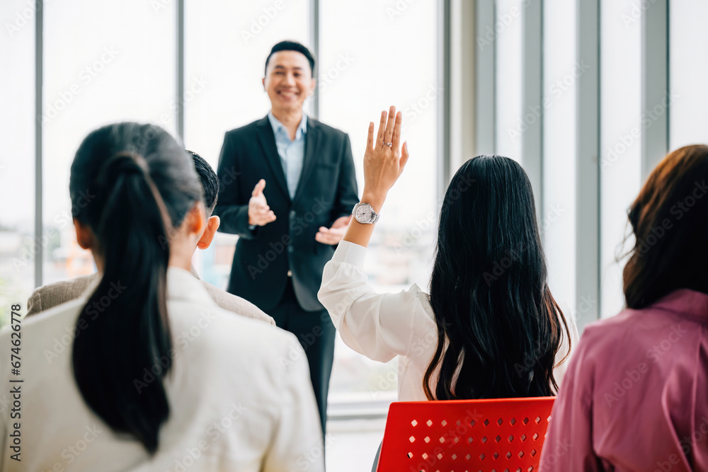 In a conference, business professionals raise their hands to ask ...