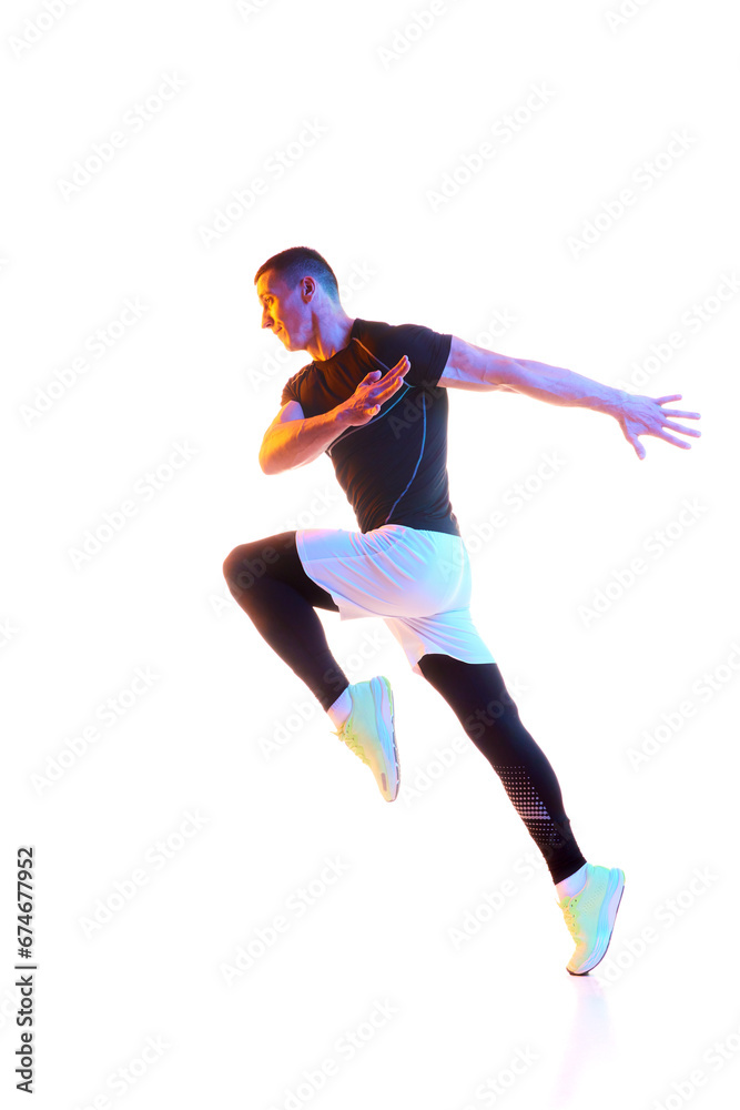 Full-length dynamic image of young man in sportswear training, running ...