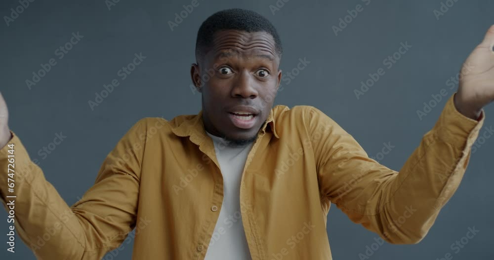 Slow motion portrait of confused and desperate man spreading arms and ...