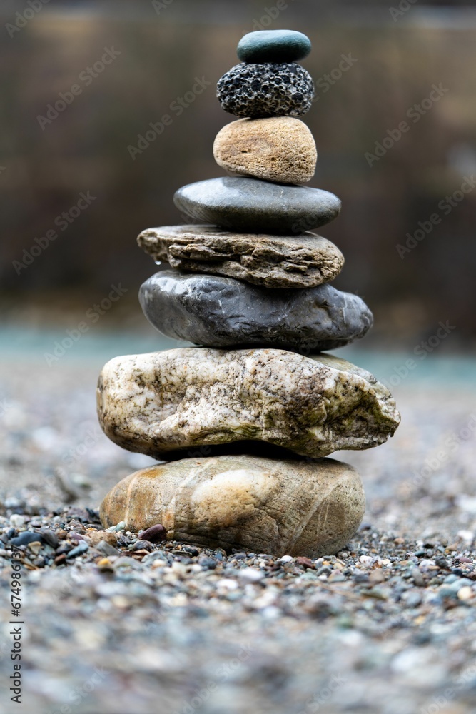 Vertical sot of stacked pebbles at the beach with a blurry background ...