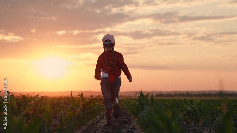 Kid runs in rubber boots on field with sprouts. Happy little girl ...