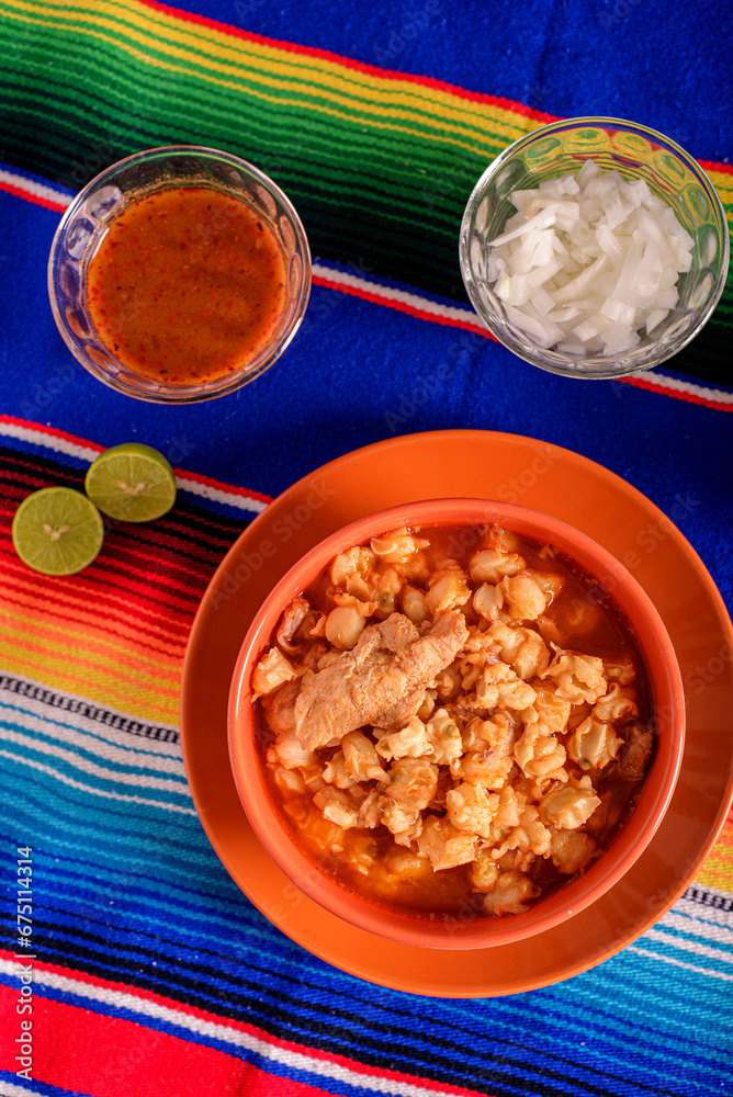 Red pozole served in a deep dish on colorful serape. Typical Mexican ...