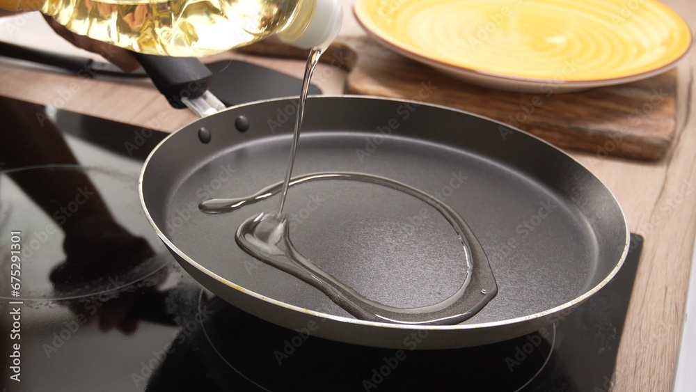 Pouring oil into frying pan. A close-up view captures the moment oil is ...