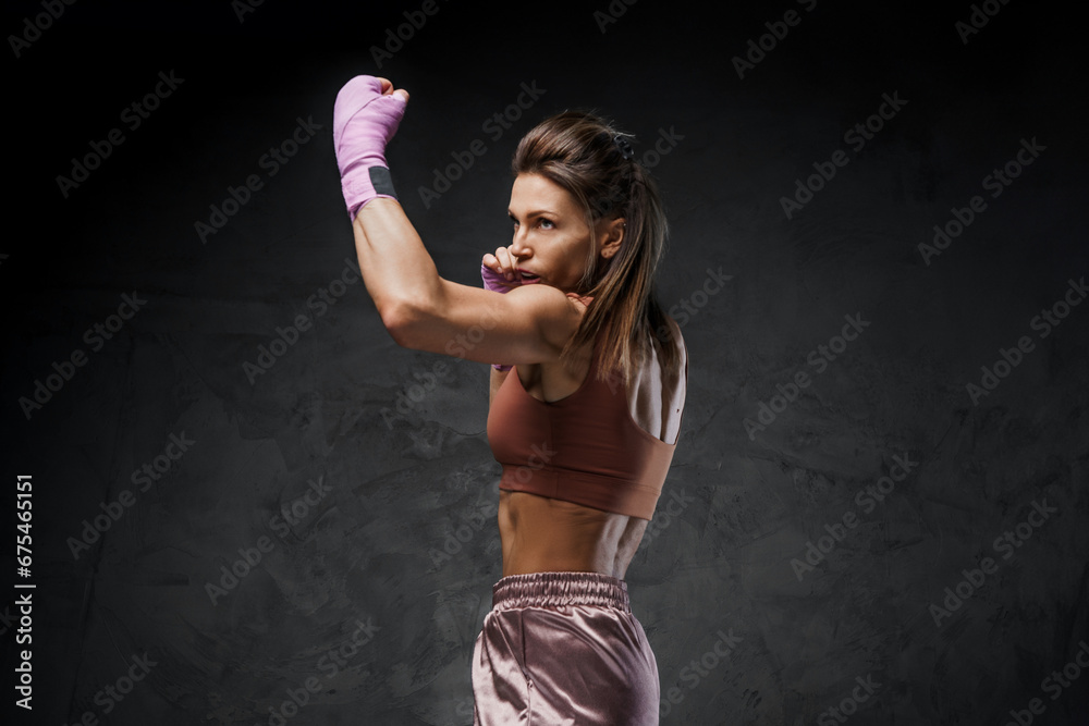Muscular woman boxer demonstrating striking skills, dressed in sports ...