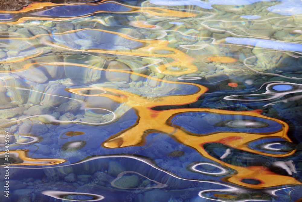 Blue water with yellow green ripples on the surface. Defocused blurred ...