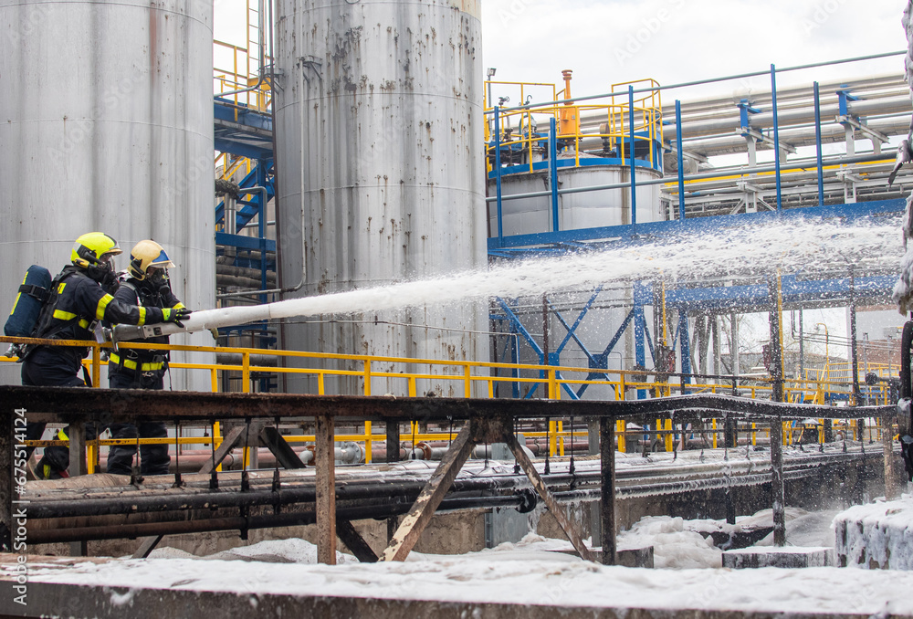 Firefighters with breathing apparatus use foam to extinguish a fire of ...