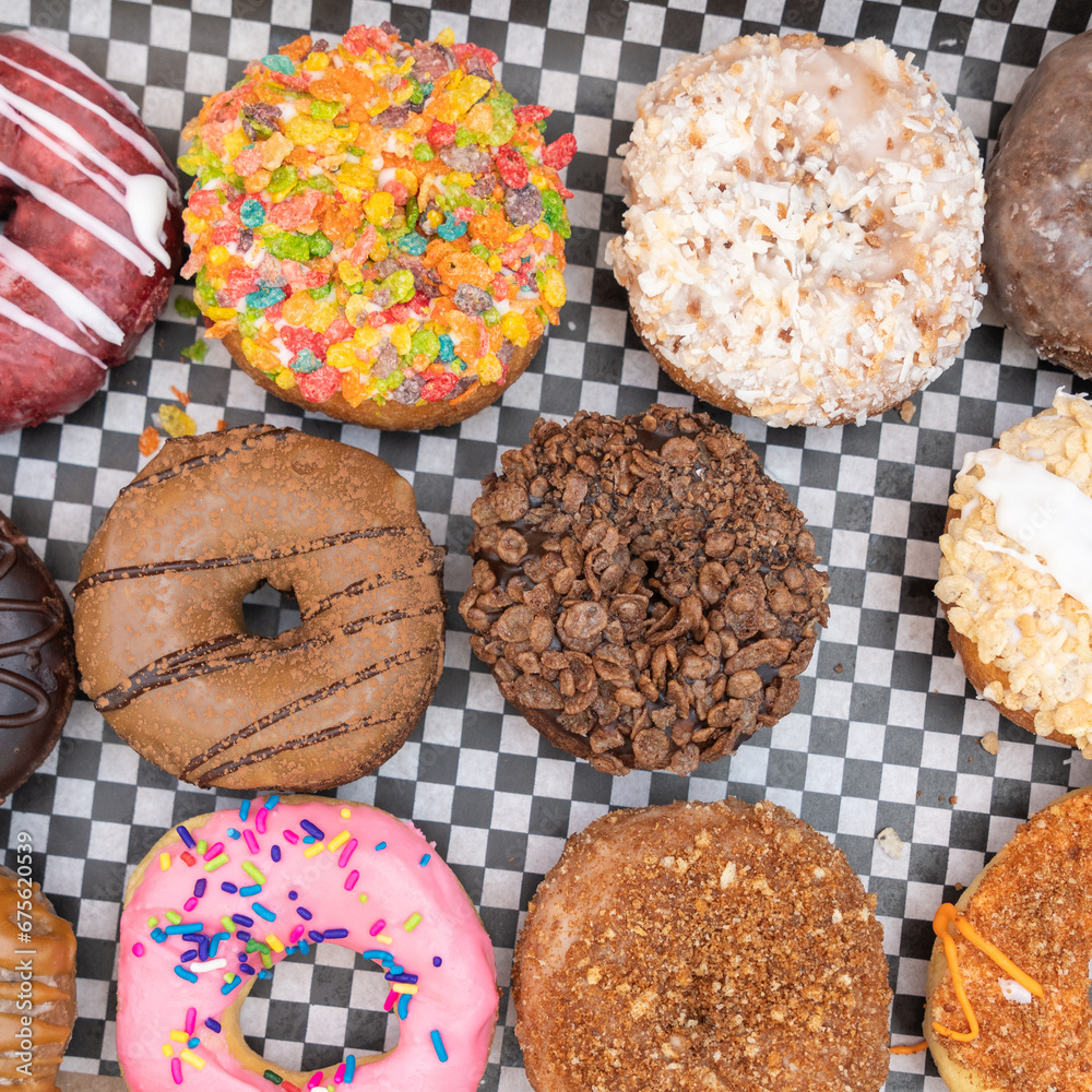 Detail of a dozen gourmet donuts placed atop a black and white ...