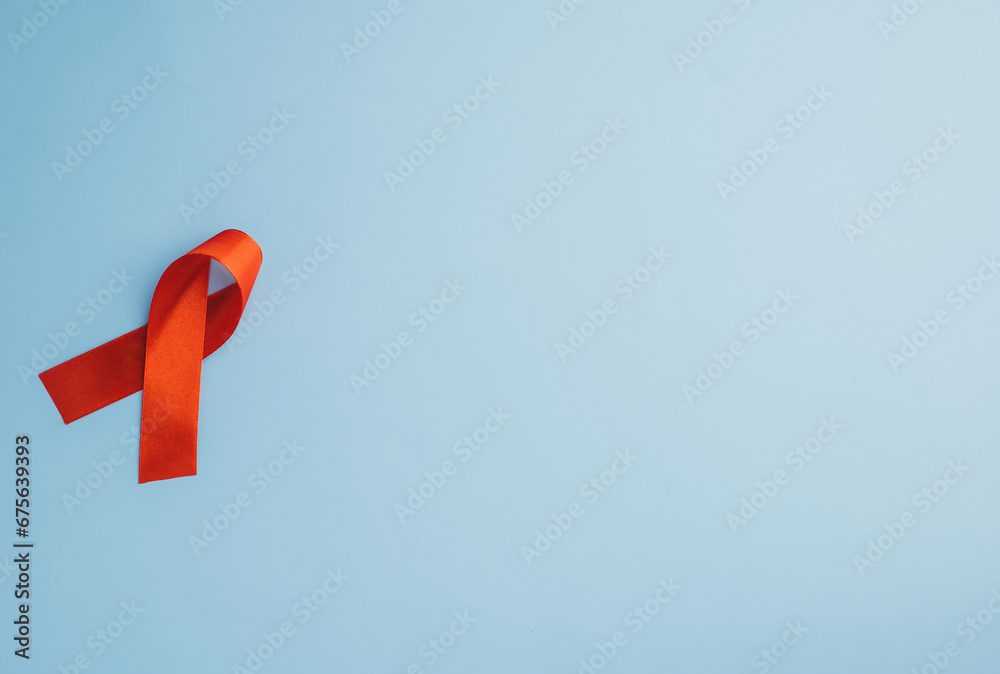 Against a blue backdrop, a red ribbon serves as a symbol of AIDS ...