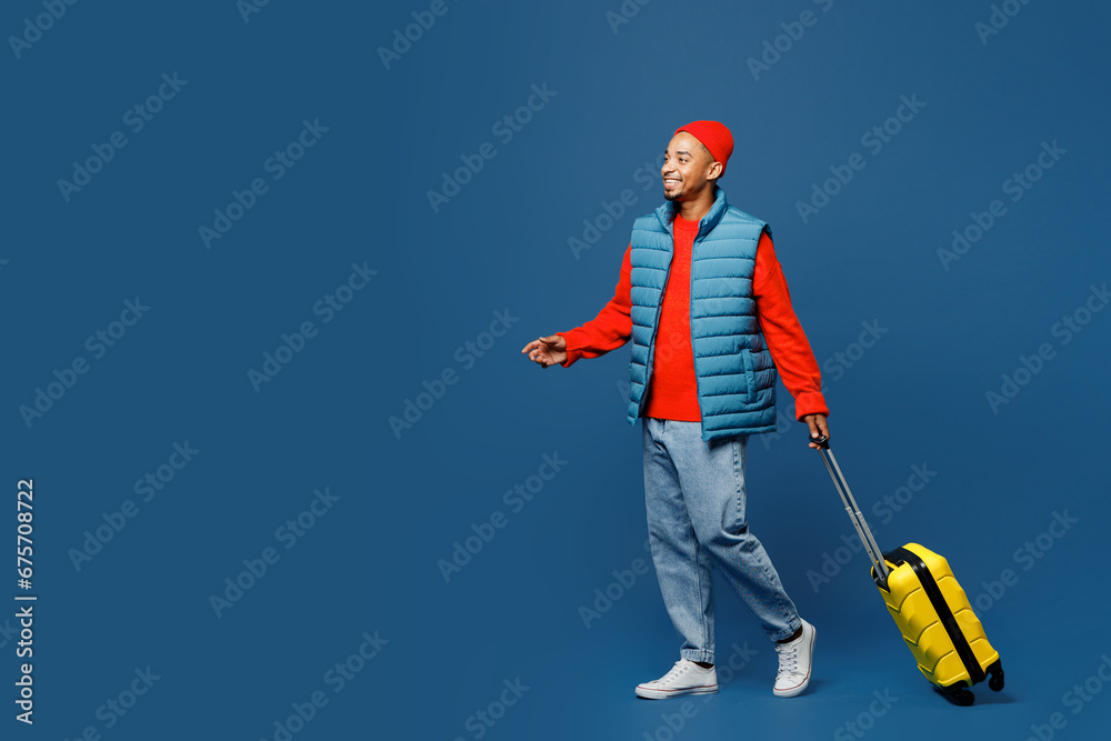 Full body traveler man wear padded vest hold suitcase walk go isolated ...