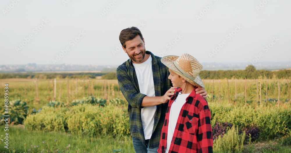 Farmer father son walking together in vegetables field. Man farmer ...