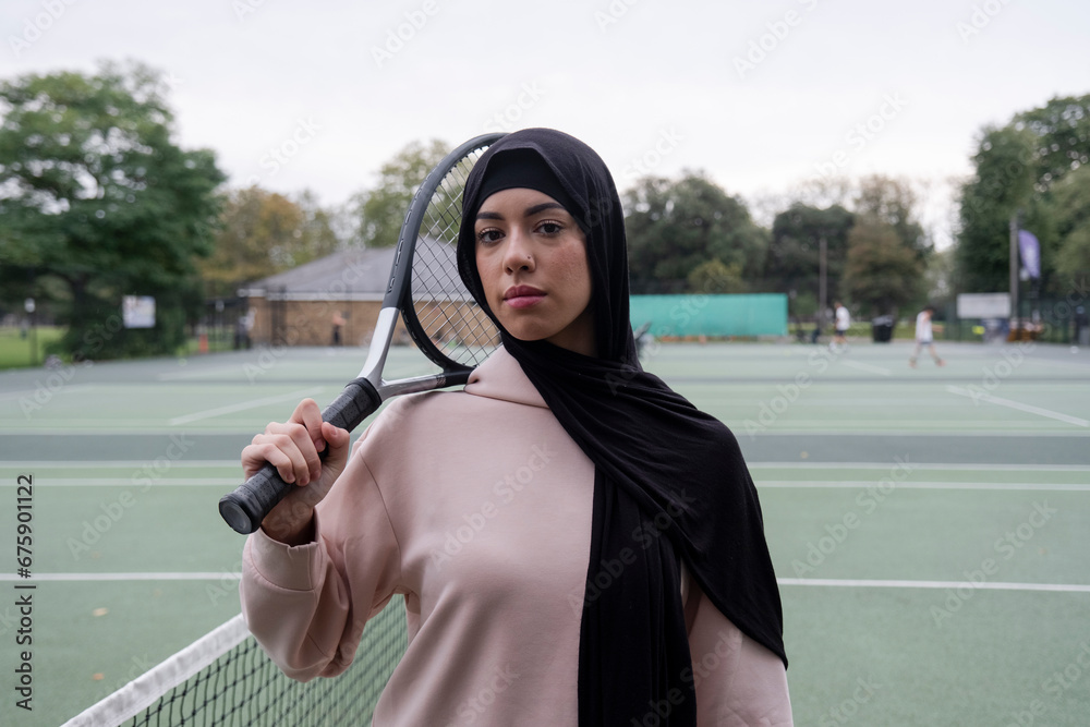 Portrait of woman in hijab holding tennis racket at tennis court Stock ...
