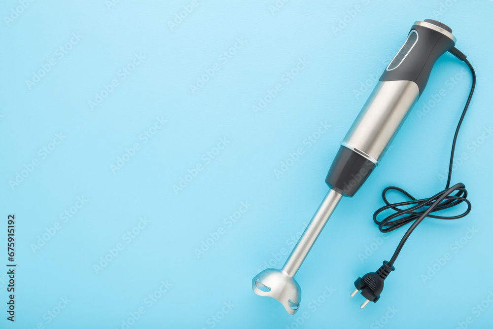 New hand blender with black wire on blue table background. Pastel color ...