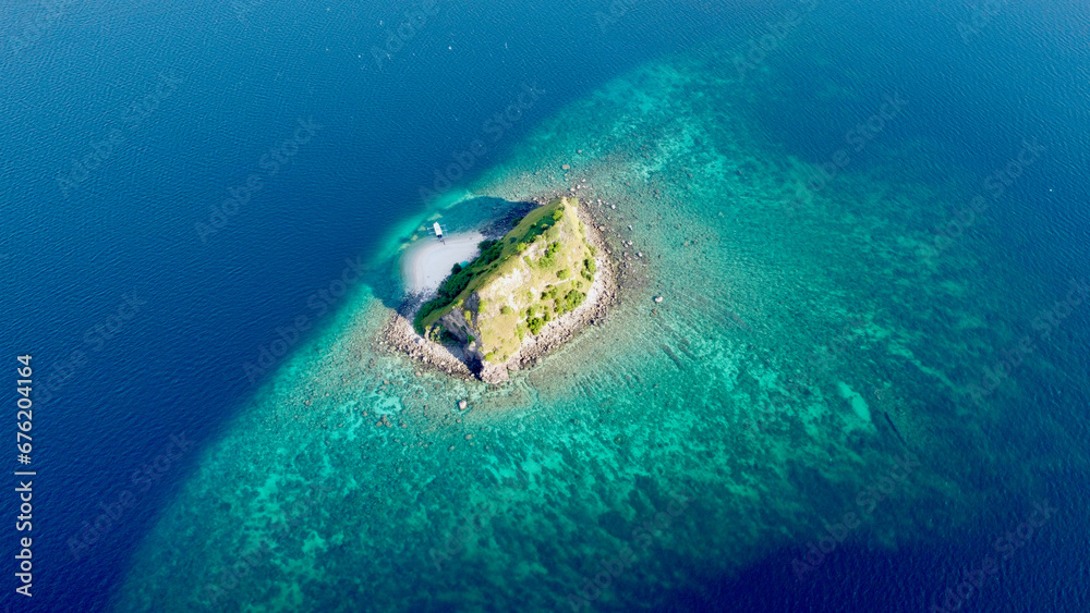 Tropical island in the open sea. Aerial view of a small rocky ...