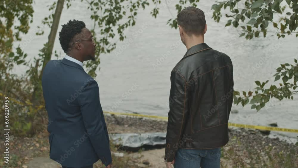 Medium back view shot of two multiethnic crime investigators having ...