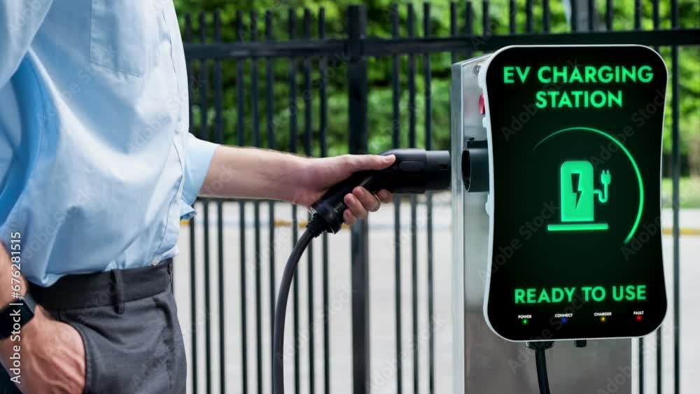 Businessman pull out EV charger from charging station to recharge ...