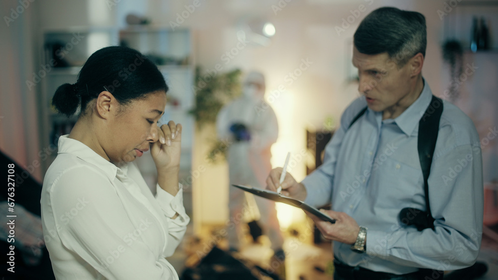 A shocked woman is talking to a detective at the crime scene, serving ...
