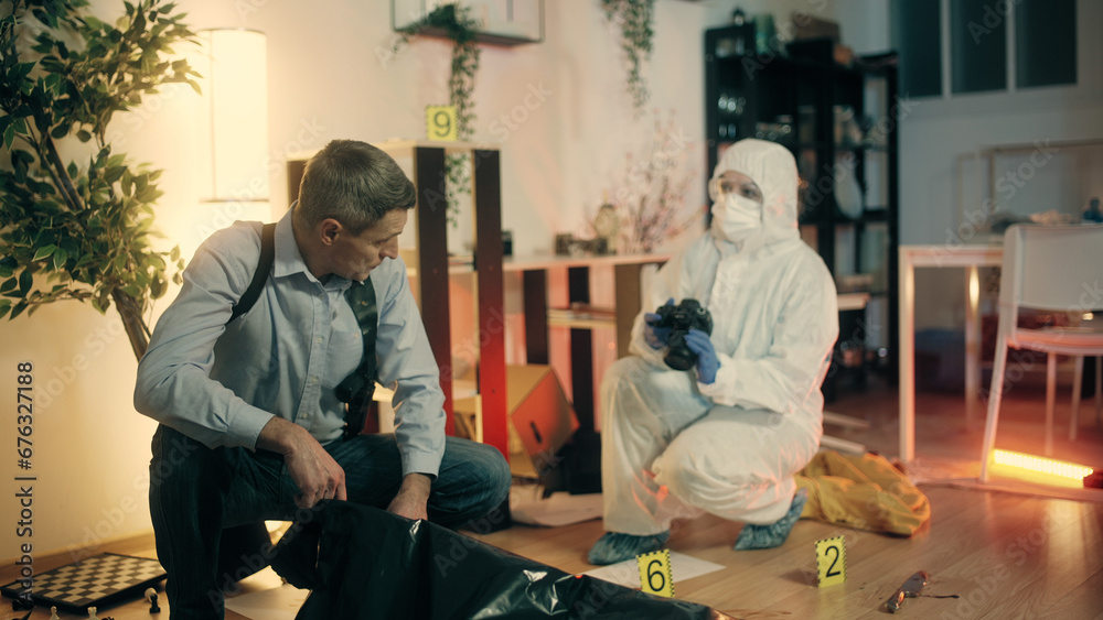 The detective is looking at the crime scene and talking to the forensic ...