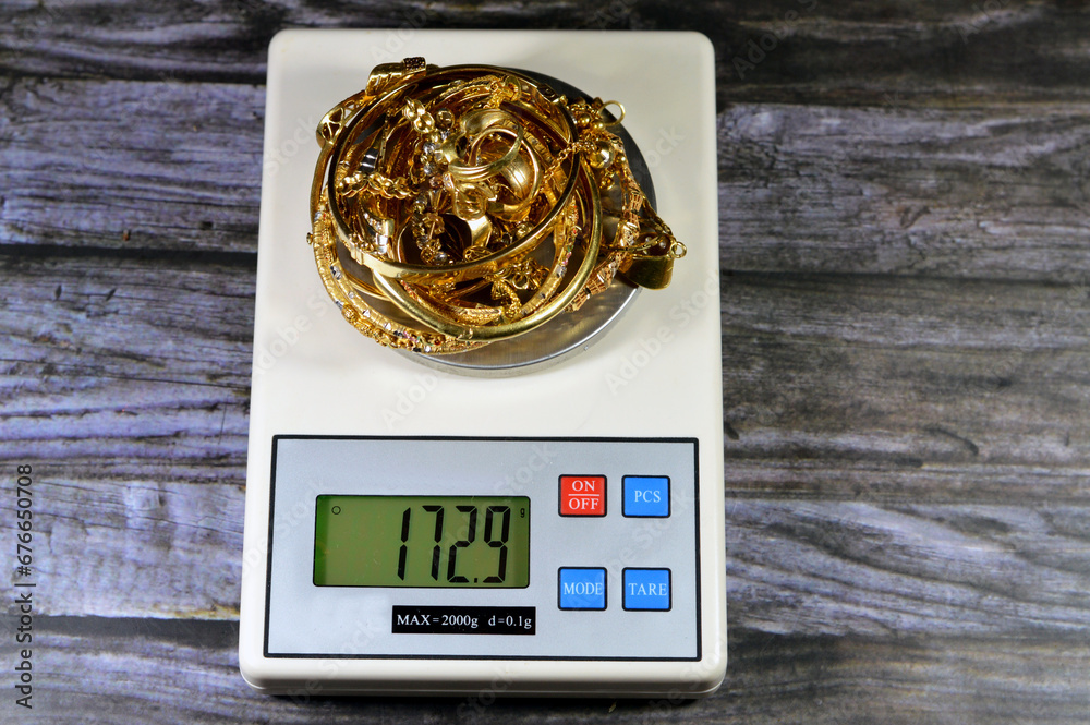 Pile stack of gold on a digital accurate scale in grams, bracelets ...