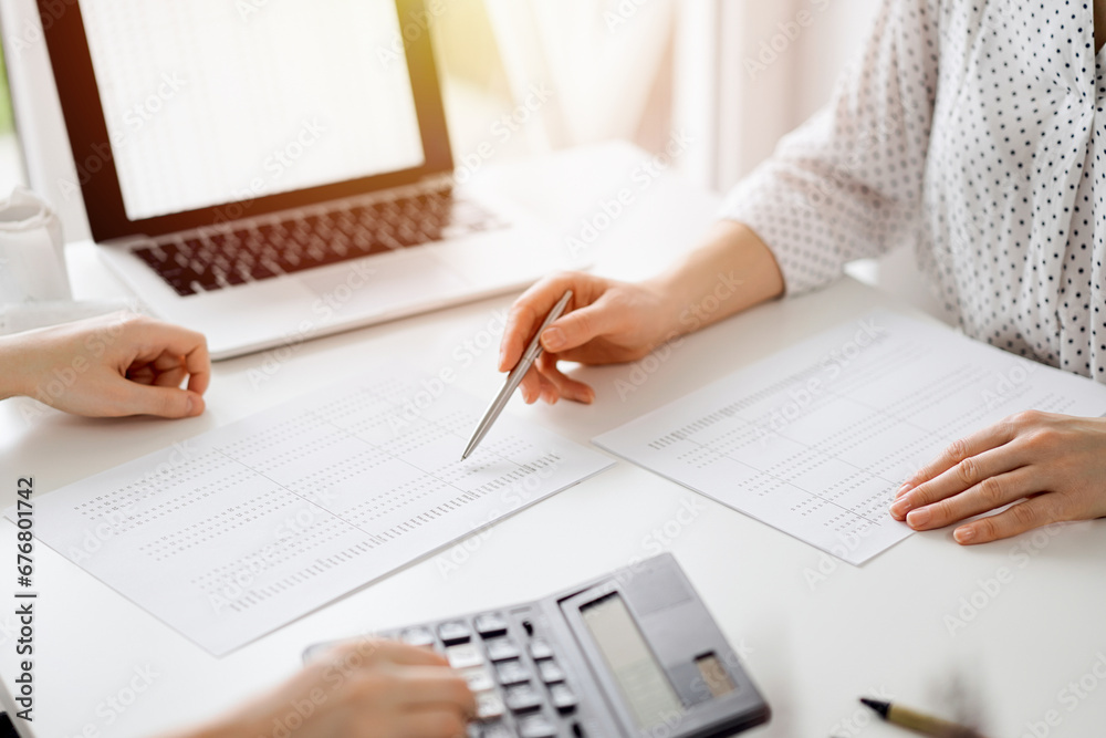 Accountant using a calculator and laptop computer for counting taxes ...