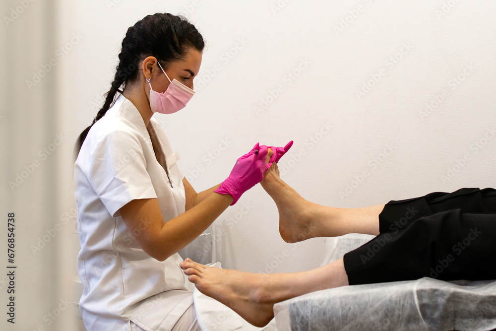 Pedicure master in medicine mask cutting of cuticle nails of feet ...