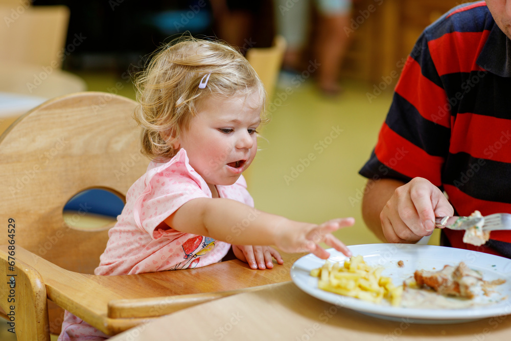 Toddler girl eating healthy vegetables and unhealthy french fries ...