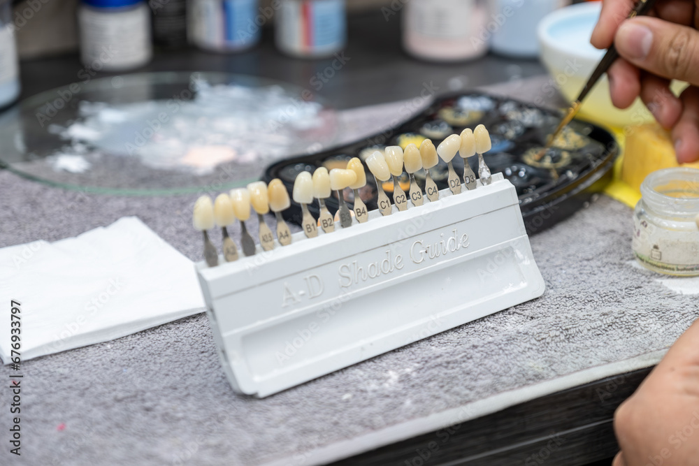 male checking A-D shade guide for tooth crowns to select the proper ...