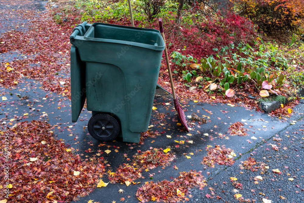 Yard waste bin, rake, and plastic shovel ready to clean up fallen ...