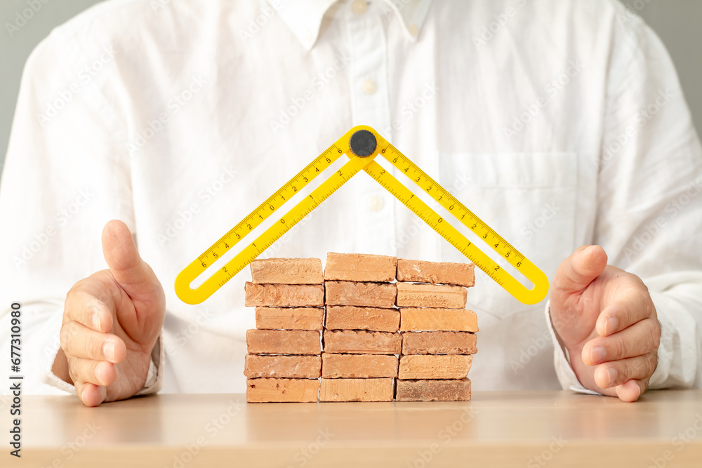Businessman hand holding a folding ruler in the shape of a house on the ...