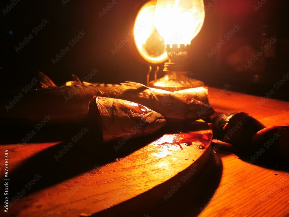 dead fish with kerosene lamp and lamp light illumination. Dead mackerel ...