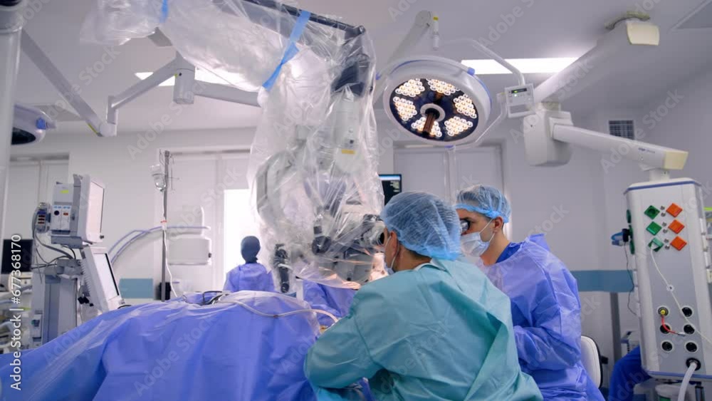 Professional neurosurgeons operating the patient looking at microscope ...